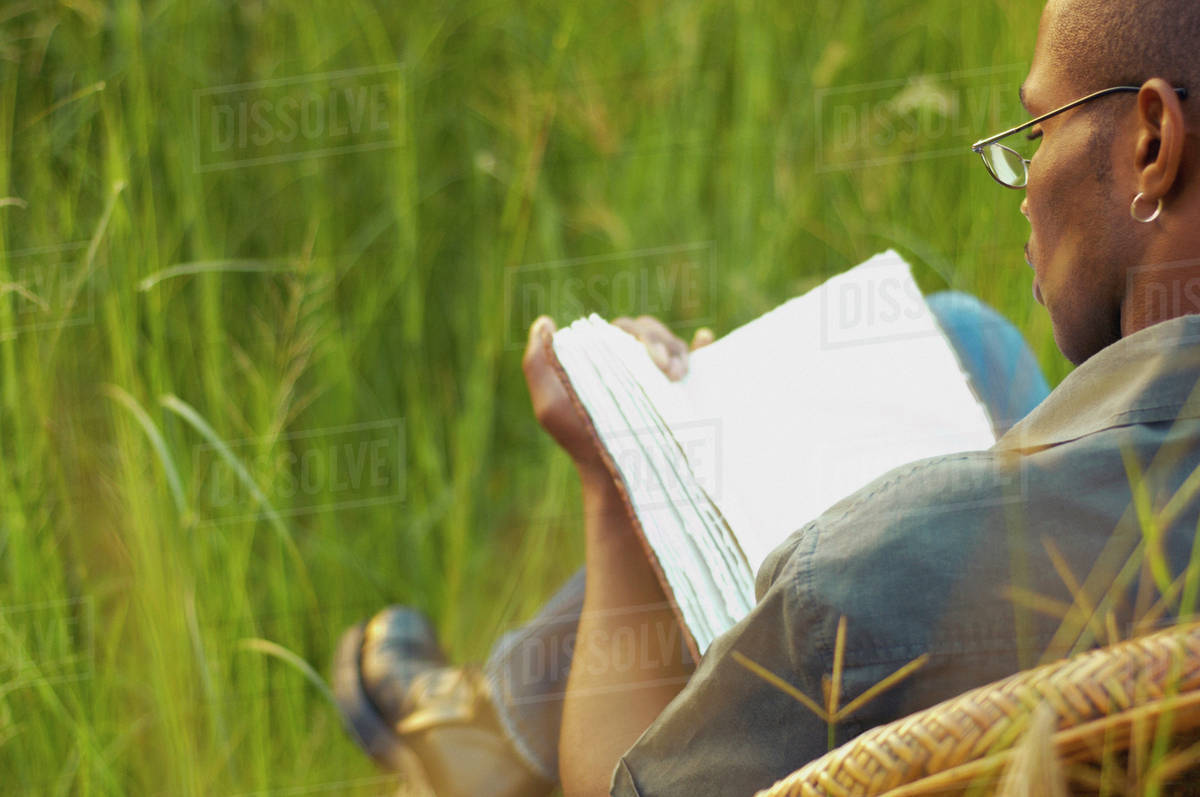 African man reading in field - Royalty-free Stock Photo | Dissolve