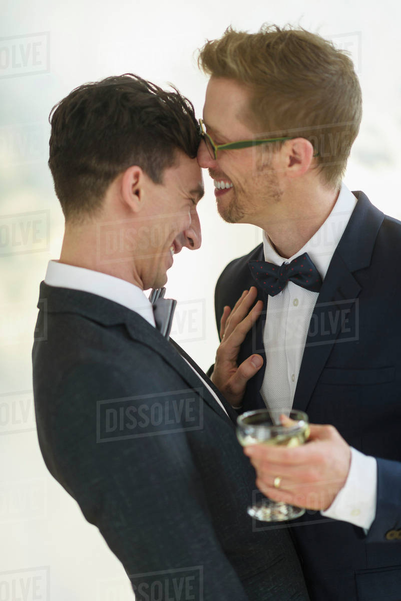 Caucasian gay grooms drinking champagne at wedding - Stock Photo - Dissolve