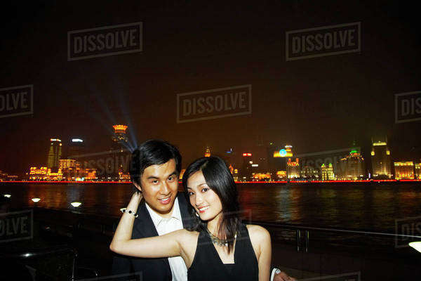 Chinese couple hugging on city waterfront - Stock Photo - Dissolve