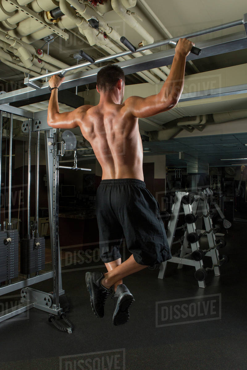 Caucasian athlete doing pull-ups in gymnasium - Stock Photo - Dissolve