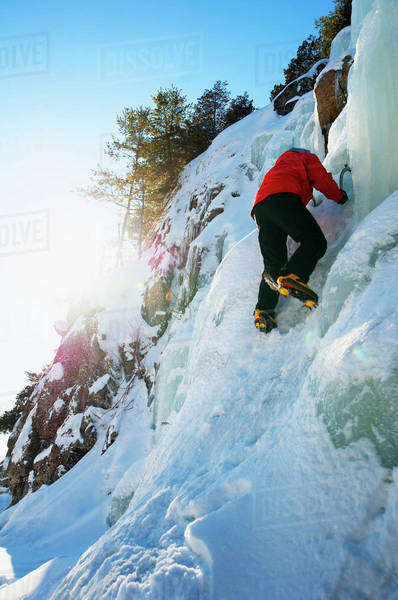 Ice climber scaling snowy frozen rock formations - Stock Photo - Dissolve