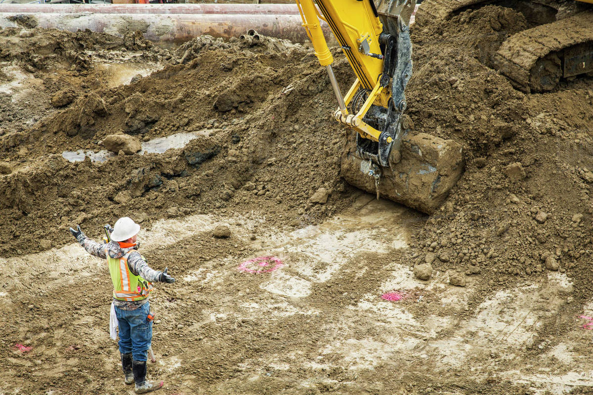 Caucasian worker directing digger at construction site - Royalty-free ...