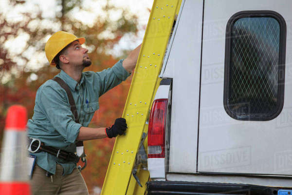 Caucasian worker loading ladder on truck - Royalty-free Stock Photo ...