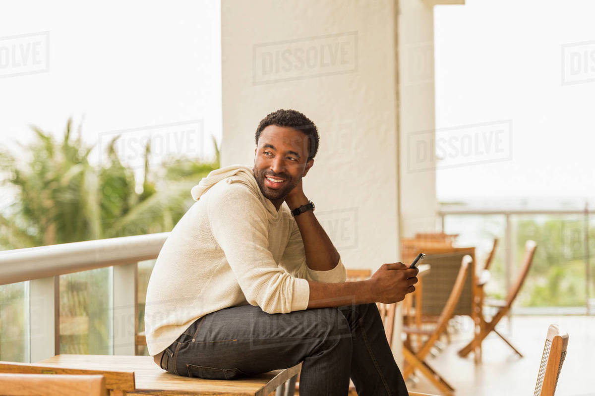 Black man using cell phone on balcony - Royalty-free Stock Photo | Dissolve