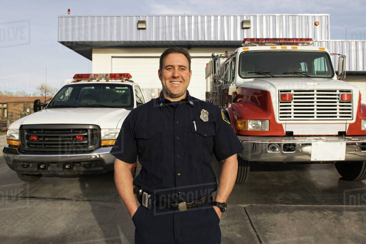 Caucasian firefighter smiling near fire trucks - Royalty-free Stock ...