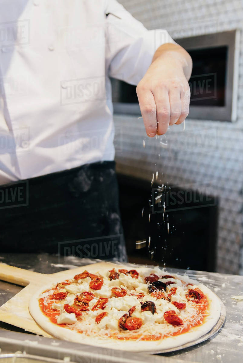 Chef making pizza in restaurant in kitchen - Stock Photo - Dissolve