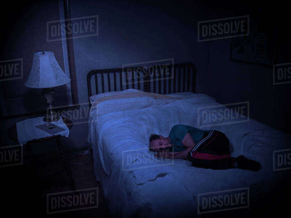 Caucasian man laying in sinking bed - Royalty-free Stock Photo | Dissolve