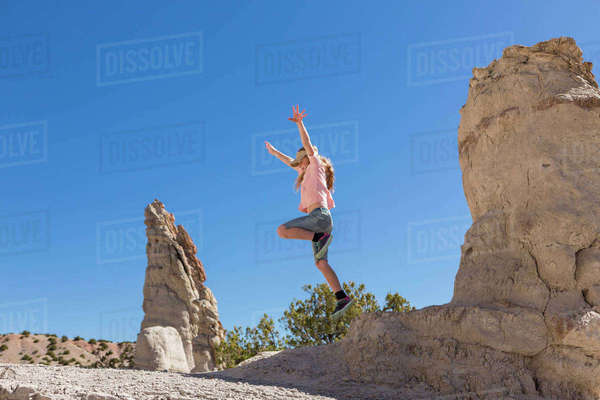 Caucasian girl jumping off rock formation - Royalty-free Stock Photo ...