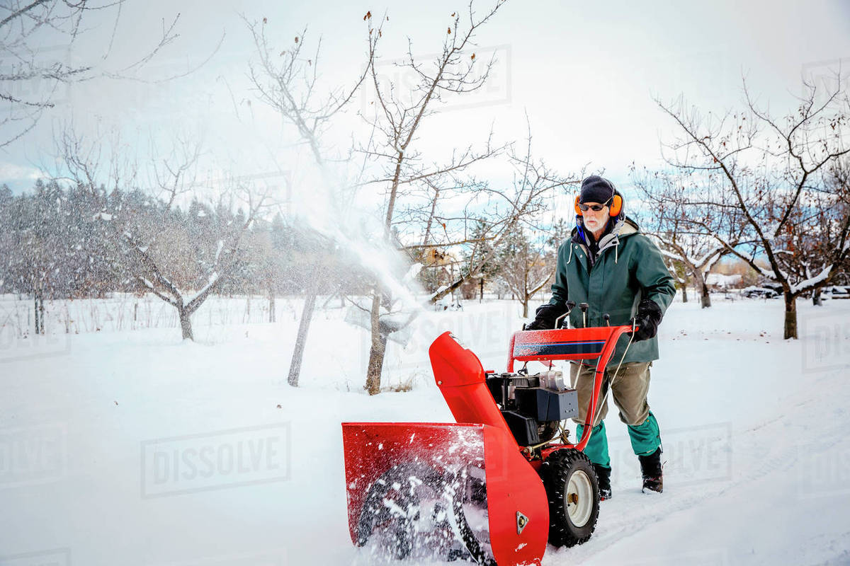 Caucasian man using snow blower in snowy field - Royalty-free Stock ...