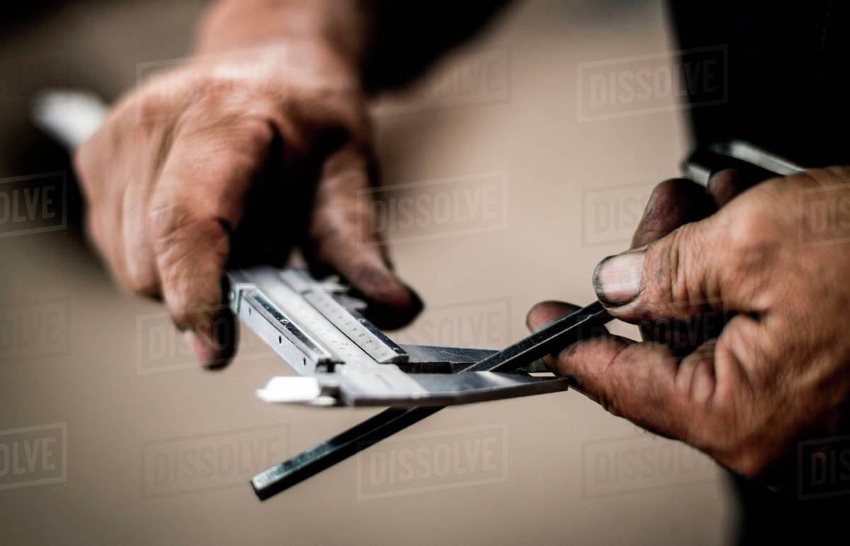 Close up of worker measuring metal - Royalty-free Stock Photo | Dissolve