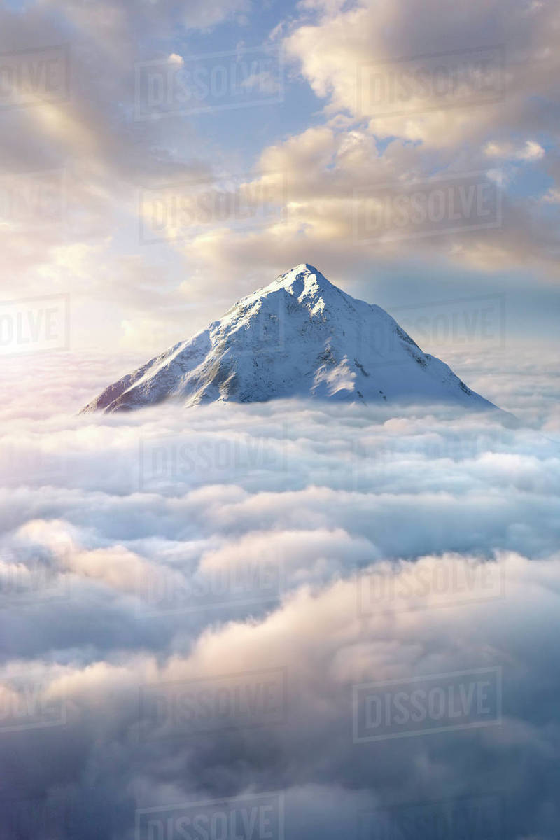 Snow-covered mountaintop above clouds - Stock Photo - Dissolve