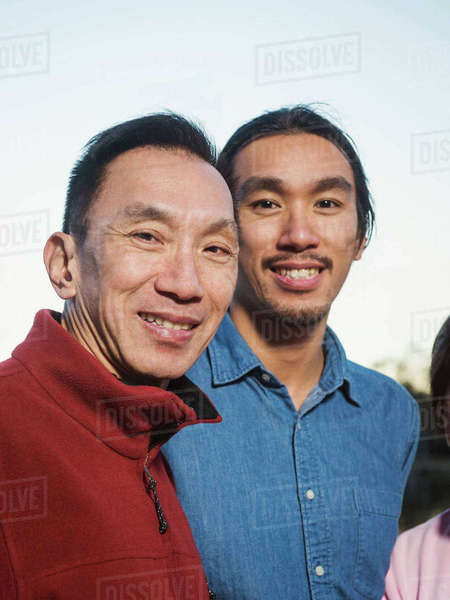 Chinese father and son smiling outdoors - Stock Photo - Dissolve