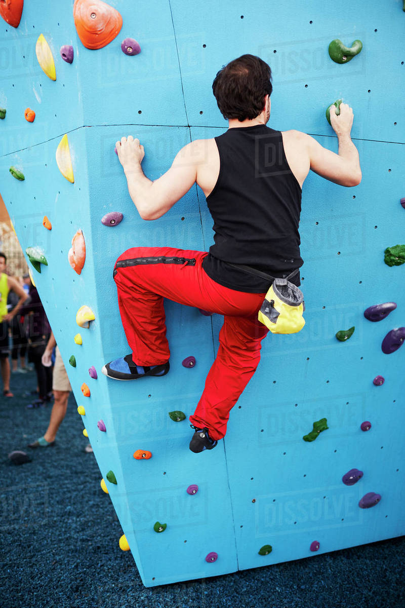 Caucasian man climbing outdoor climbing wall - Stock Photo - Dissolve