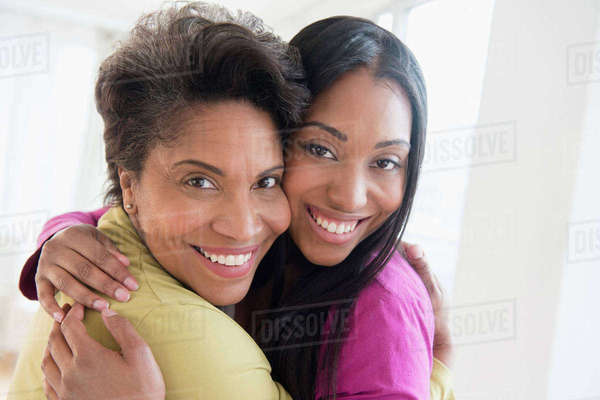 Black women hugging cheek to cheek - Stock Photo - Dissolve