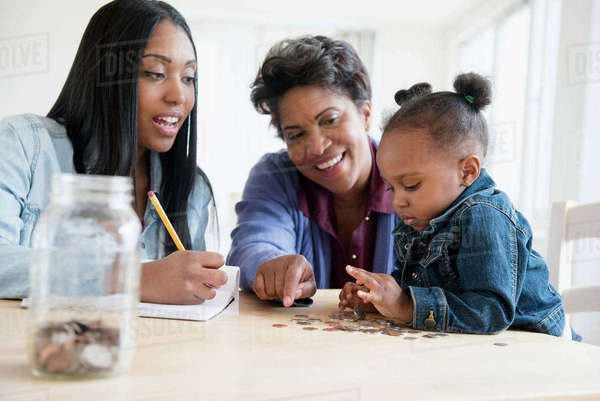 Black multi-generation family counting coins - Stock Photo - Dissolve