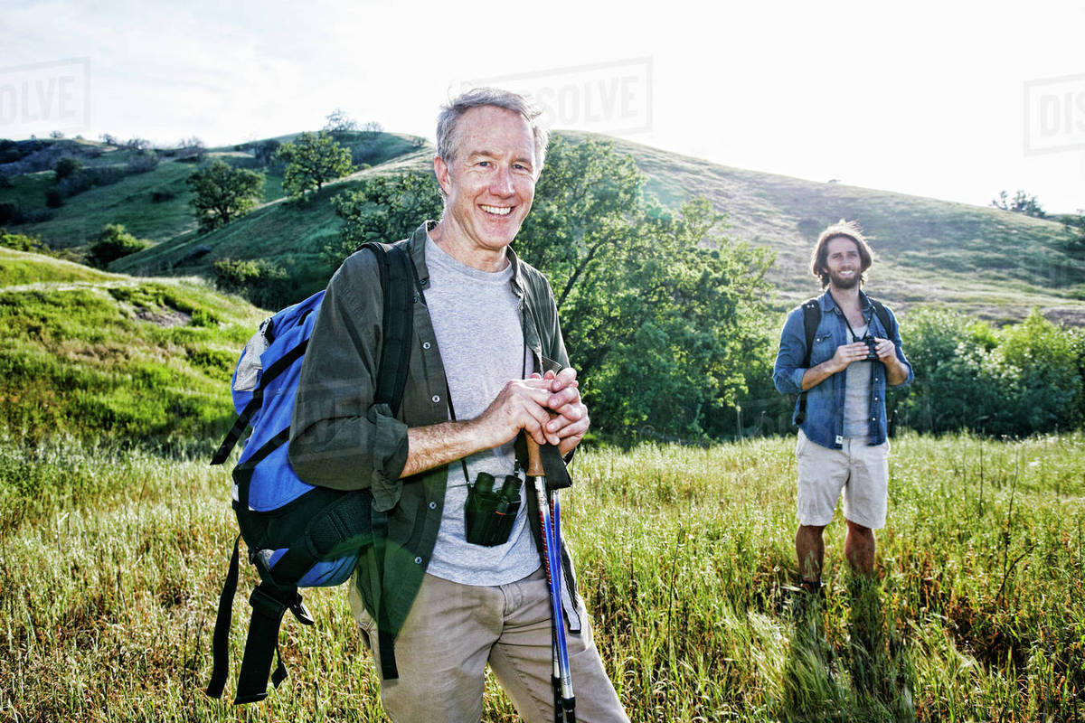 Caucasian hikers standing in grass on mountain - Royalty-free Stock ...