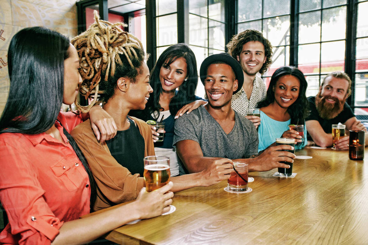 Smiling friends drinking at table in bar - Royalty-free Stock Photo ...