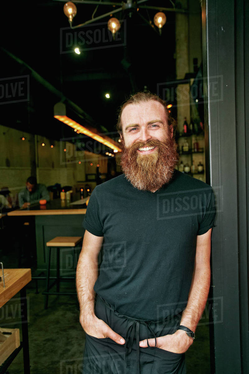 Smiling Caucasian man with beard leaning in doorway - Royalty-free ...