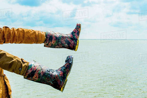 Person wearing boots on hands over water - Stock Photo - Dissolve