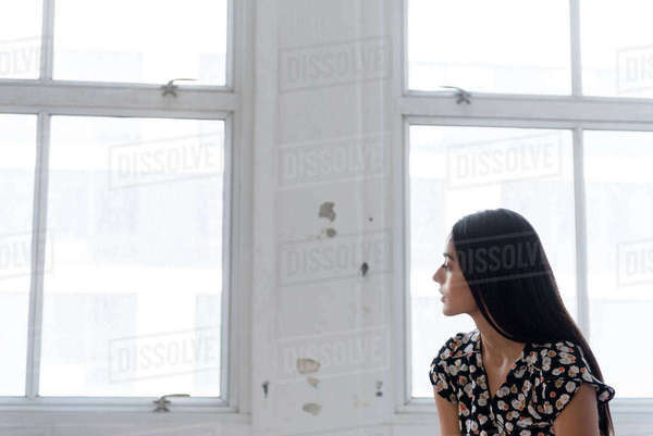 Pensive Indian woman sitting near window - Stock Photo - Dissolve