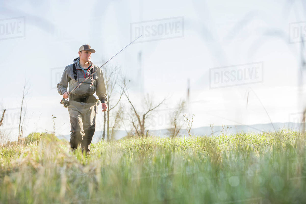 Caucasian man carrying fishing rod in field - Royalty-free Stock Photo ...