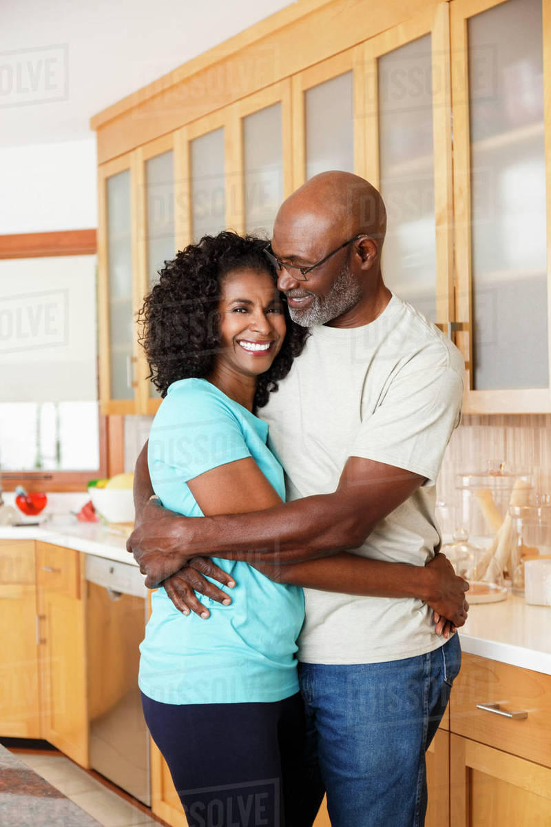 Black couple hugging in kitchen - Royalty-free Stock Photo | Dissolve