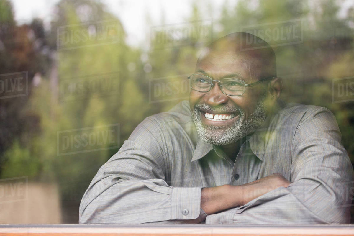 Smiling Black man behind window - Stock Photo - Dissolve