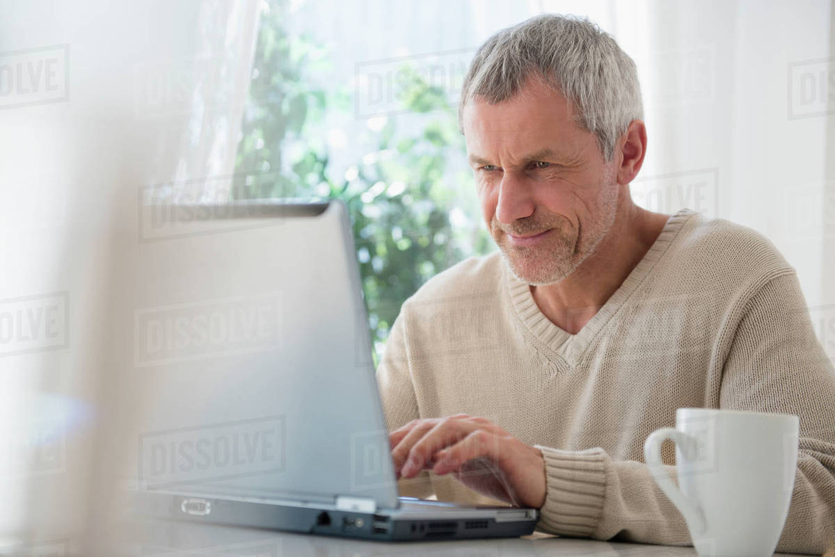 Older Caucasian man using laptop - Stock Photo - Dissolve
