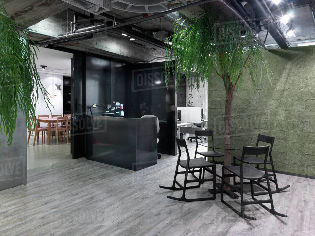 Modern circular table with tree in center in industrial office building ...