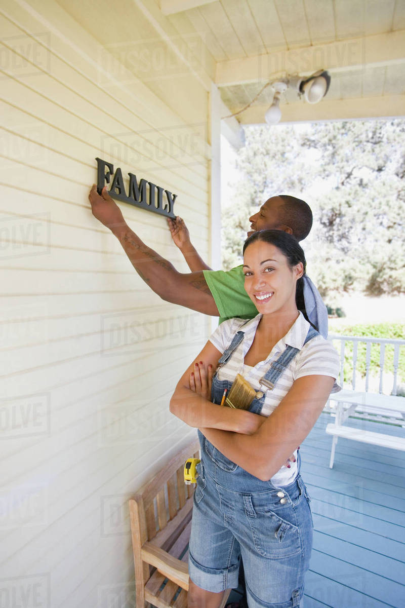 Couple hanging family sign on house - Royalty-free Stock Photo | Dissolve