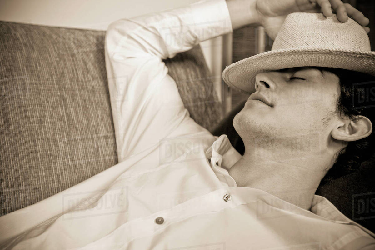 Mixed race man sleeping on sofa with hat over face - Royalty-free Stock ...