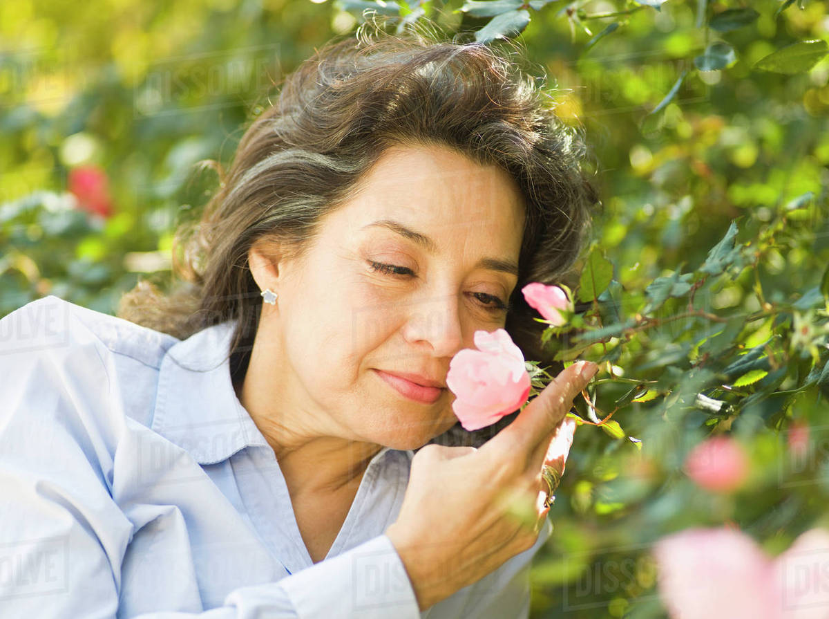 Caucasian woman smelling flower outdoors - Royalty-free Stock Photo ...