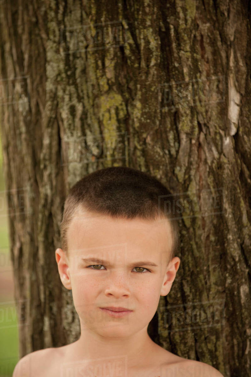 Caucasian boy leaning against tree trunk - Royalty-free Stock Photo ...