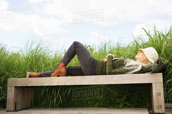 Caucasian woman laying on bench - Royalty-free Stock Photo | Dissolve