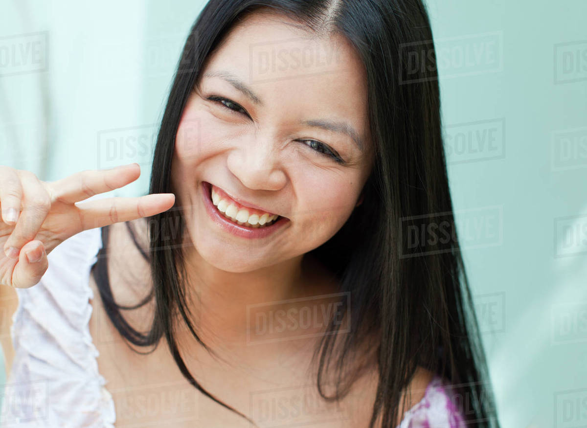 Smiling Vietnamese woman making peace sign gesture - Royalty-free Stock ...