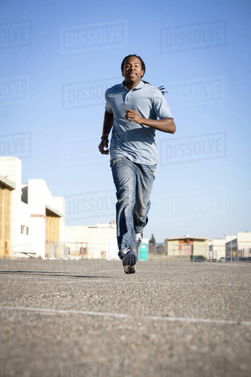 Black man running in parking lot - Royalty-free Stock Photo | Dissolve