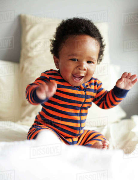 African American boy sitting on bed - Stock Photo - Dissolve