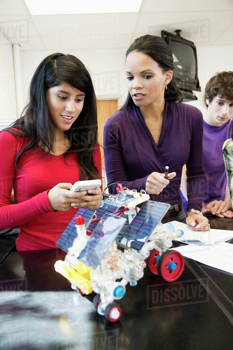 High school students working on solar powered machine in classroom ...