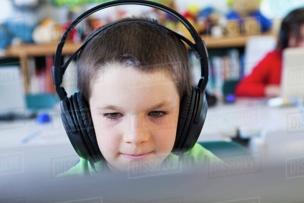 Caucasian student in headphones using laptop in classroom - Royalty ...
