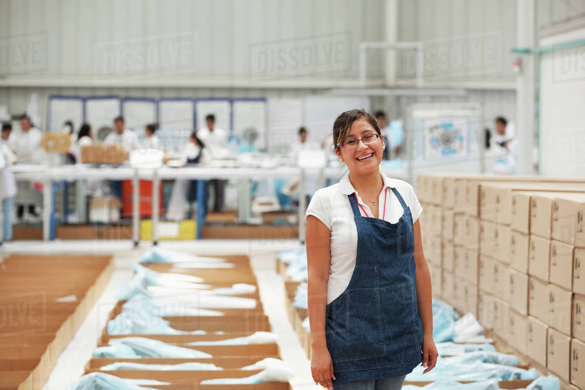 Worker smiling in manufacturing plant - Royalty-free Stock Photo | Dissolve