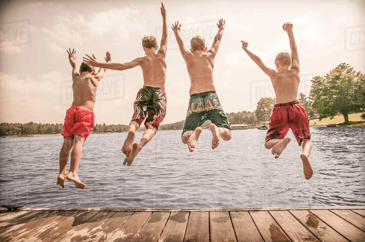 Caucasian boys jumping off wooden dock - Royalty-free Stock Photo ...