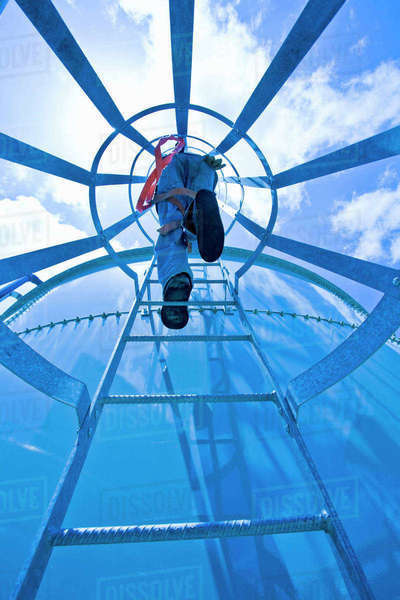 Man climbing water tower ladder - Royalty-free Stock Photo | Dissolve