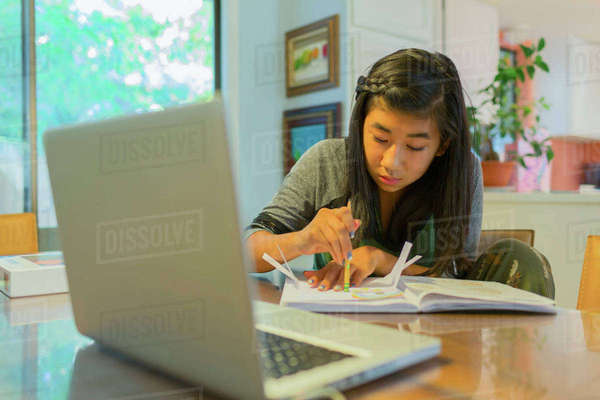 Chinese girl doing homework at table - Stock Photo - Dissolve