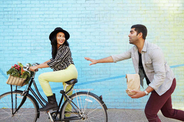 Indian man chasing girlfriend on bicycle - Stock Photo - Dissolve