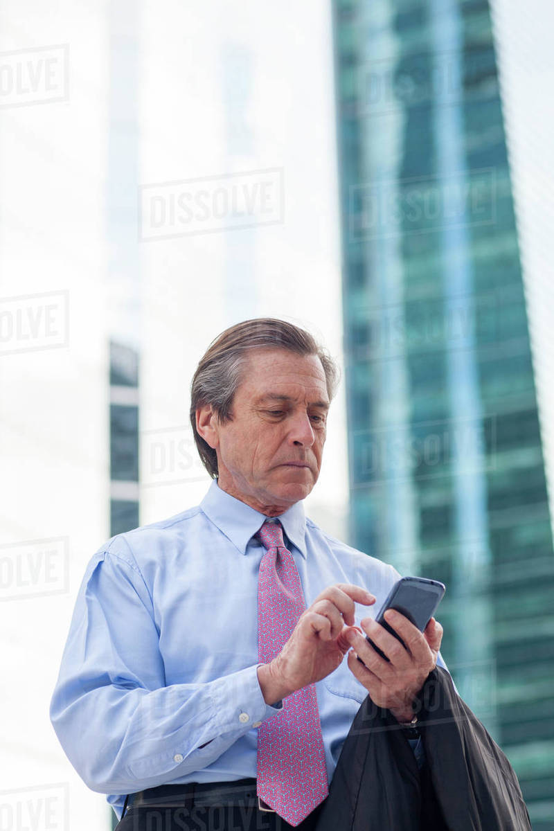 Caucasian businessman using cell phone outside highrise - Royalty-free ...