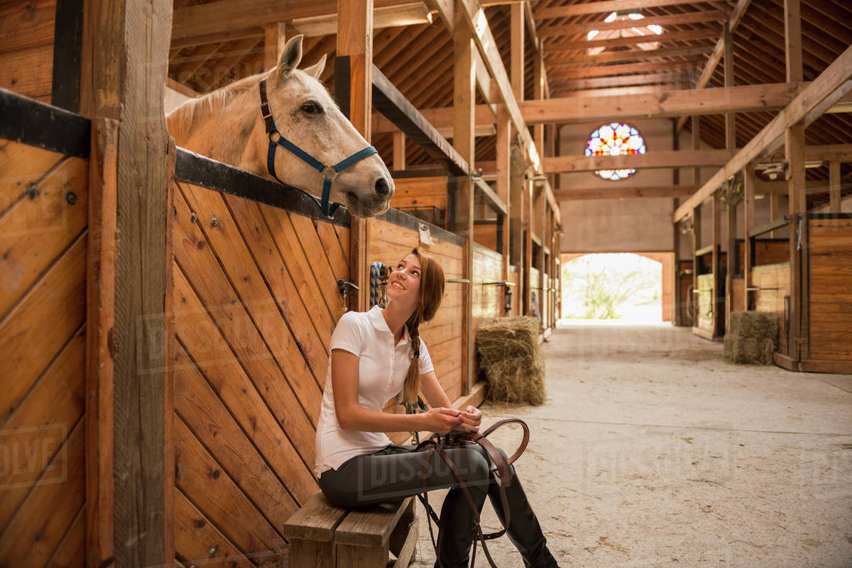 Caucasian girl sitting with horse in stable - Royalty-free Stock Photo ...
