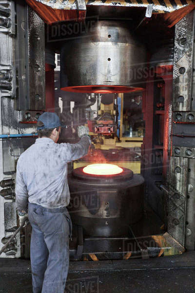 Caucasian worker operating steel melting machinery in factory - Royalty ...