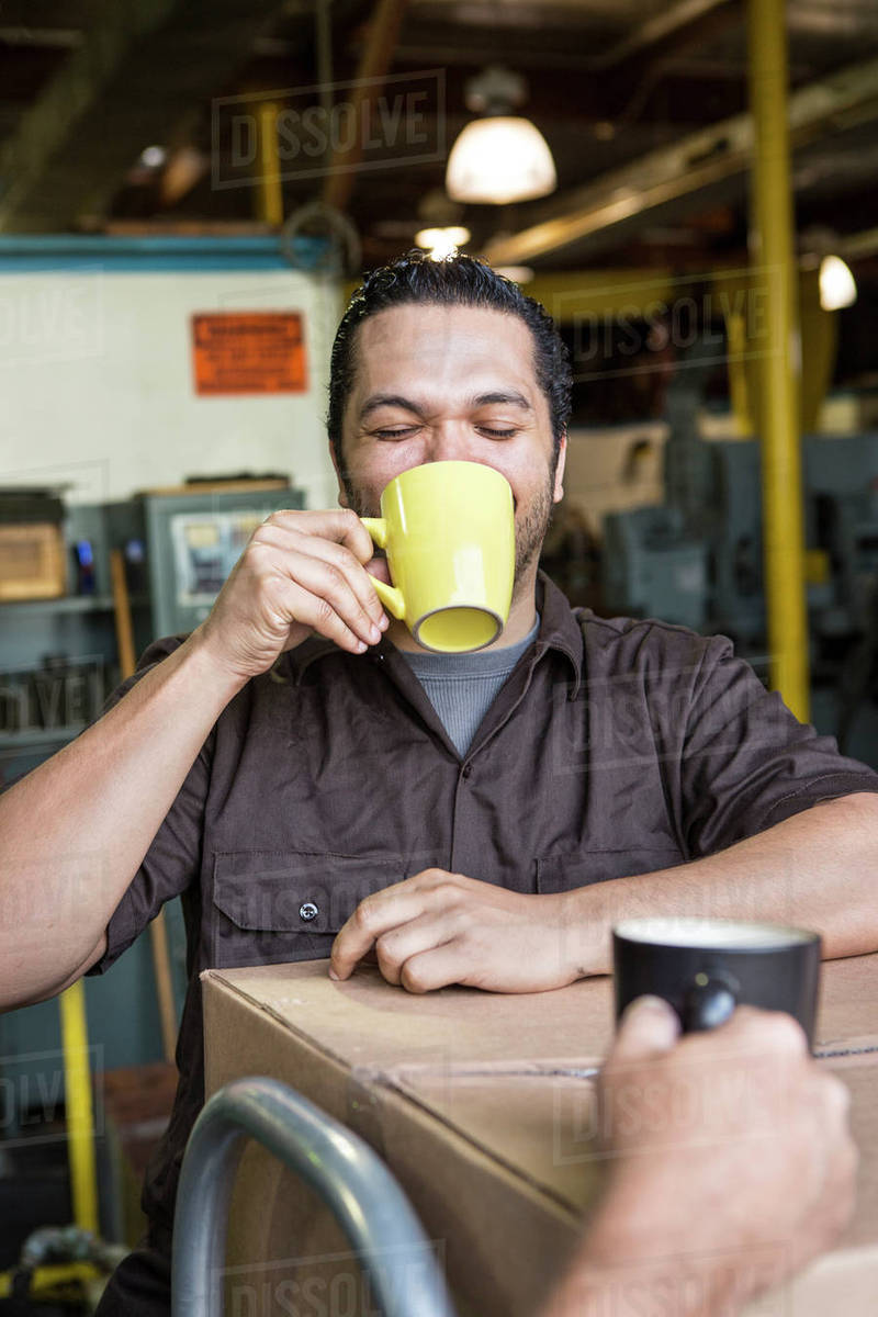Worker drinking coffee in warehouse - Stock Photo - Dissolve