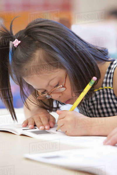 Mixed race Down syndrome student writing in workbook - Royalty-free ...