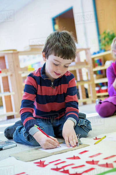 Caucasian boy drawing in classroom - Royalty-free Stock Photo | Dissolve